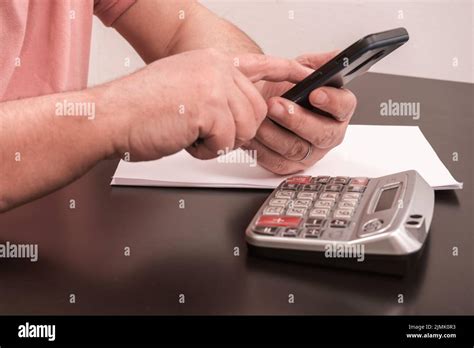 Unrecognizable Latino Adult Male Checking Messages On His Cell Phone While Doing Math With Unrecognizable Latino Adult Male Checking Messages On His Cell Phone While Doing Math With