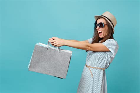 세로 행복 여름 패키지 가방을 들고 드레스 밀 짚 모자 구매 후 블루 파스텔 배경에 고립 쇼핑에 웃는 아름 다운 백인 여자 흥분 광고에 대 한 공간을 복사 가방에 대한 스톡