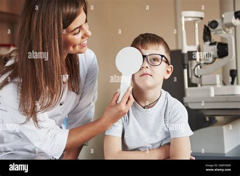 Favorite Job Female Doctor Covers Right Kid Eye With Medical Tool For Checking Visual Acuity