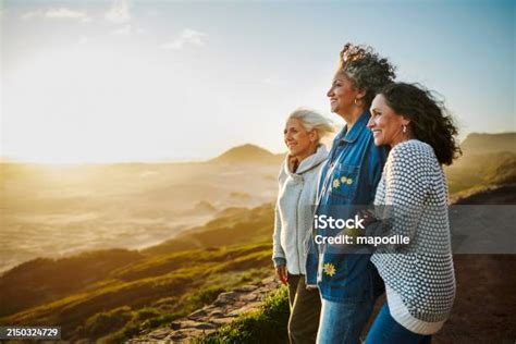 로드 트립 중 경치 좋은 해안가에서 팔짱을 끼고 서 있는 미소 짓는 성숙한 친구들 여자에 대한 스톡 사진 및 기타 이미지