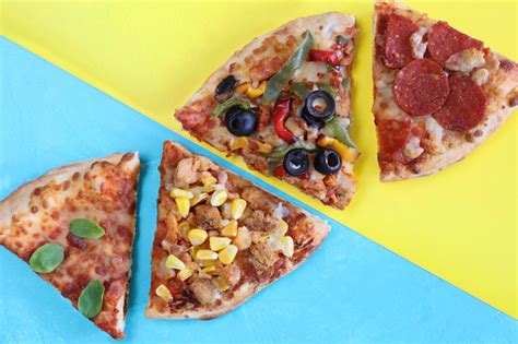 닭고기와 스위트콘 페퍼로니 피자 마르게리타 블루와 옐로우 분할 배경에 검은 올리브를 곁들인 채소 등 다양한 토핑을 얹은 4개의 피자 슬라이스를 클로즈업한 이미지 높은 전망