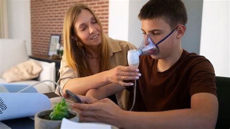 Free Photo View Of Teenage Boy Using Nebulizer At Home For