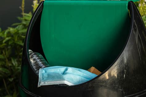 파란색 쓰레기통에 있는 의료용 얼굴 마스크는 쓰레기로 가득합니다 일회용 페이스 마스크 빈에 사용 된 얼굴 마스크를 던지는 올바른 방법 폐기 마스크의 닫는 것은 전염성