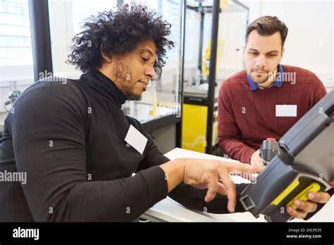 two engineers engaged in programming a robotic system with a gripper