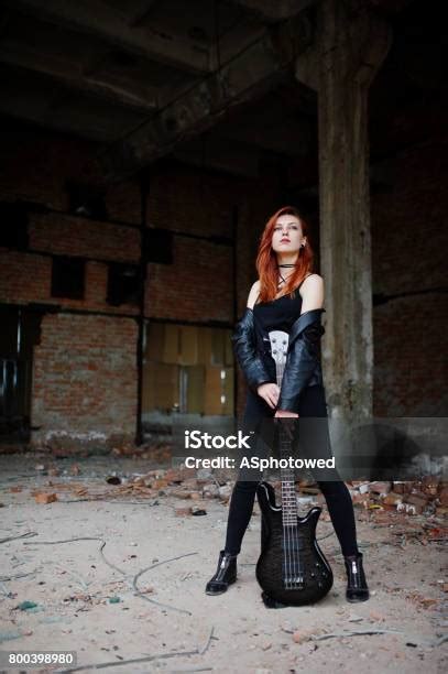 Abadoned 장소에 베이스 기타와 함께 블랙에 빨간 머리 펑크 걸 착용 고딕 여자 음악가의 초상화입니다 Hardcore Music Style에 대한 스톡 사진 및