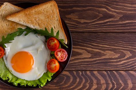 토마토 샐러드 아루굴라 삼각형 토스트를 곁들인 계란 튀김을 어두운 소박한 나무 배경에 적어 두어 오른쪽 복사 공간이 있습니다 0명에 대한 스톡 사진 및 기타 이미지 Istock