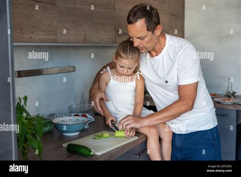 Father Patiently Teaching A His Daughter How To Cook In Their Home