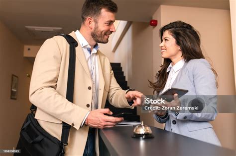 젊은 사업가 가 호텔에 체크인 태블릿에 그를 보여주는 호텔 카운터 뒤에 미소 여성 접수 호텔 리셉션에 대한 스톡 사진 및 기타 이미지 호텔 리셉션 태블릿 호텔