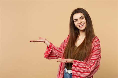 캐주얼에서 쾌활 한 젊은 여자의 초상화 카메라를 찾고 스튜디오에서 파스텔 베이 지 배경에 고립 된 손을 옆으로 가리키는 사람들은 진심으로 감정 라이프 스타일 개념입니다 복사