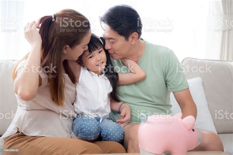 행복한 아시아 가족 아버지와 어머니는 집 거실의 소파에 앉아 뺨에 키스하는 딸 아빠와 엄마 아이는 소파 라이프스타일 관계 개념에 앉아 편안하게 휴식을 취한다 3 명에 대한