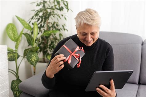 선물 상자를 든 늙은 여자가 소파에 앉아 있다 섣달 그믐 날과 크리스마스 휴가 개념 2명에 대한 스톡 사진 및 기타 이미지 2명 가정 생활 남자 Istock