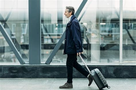 Premium Photo Side View Of Man Walking With Suitcase On Floor