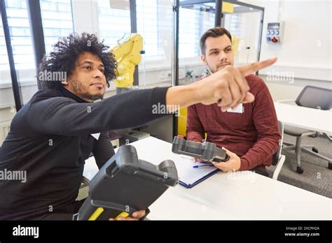 two engineers collaborating on robotics training working with gripper