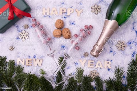샴페인 한 병 과자 선물 와인 잔이 비문 옆에 있는 축제 테이블에 놓여 있습니다 눈 덮인 배경에 새해 복 많이 받으세요 12월에