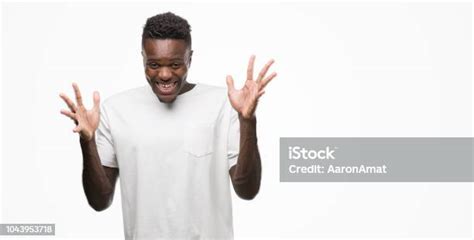 흰색 옷을 입고 젊은 아프리카계 미국인 남자가 미친과 팔 성공을 위한 깜짝 놀라게 하는 티셔츠 제기 하 고 흥분 하는 소리 오픈