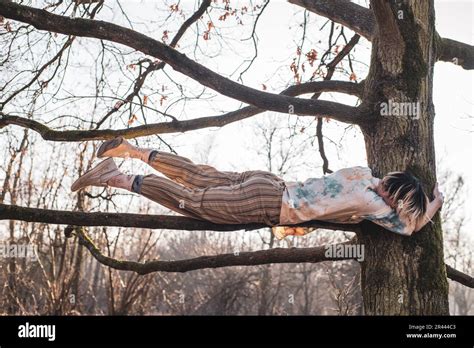 Androgynous Dancer Balances In Strong Hold Along Tree Branch Stock Photo Alamy