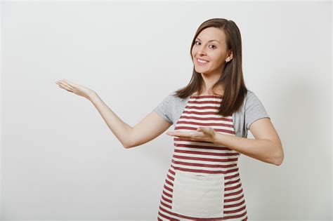 젊은 매력적인 웃는 갈색 머리 백인 주부 스트라이프 앞치마 흰색 배경에 고립에서 아름 다운가 정부 여자 가리키는 두 손을 옆으로 카메라를 찾고 광고에 대 한 공간을 복사