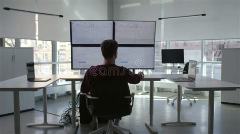 back view of it programmer work at multi screen computer workstation