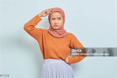 갈색 스웨터와 히잡을 입은 젊은 아시아 무슬림 여성이 흰색 배경에 고립 된 질문에 대해 진지하게 생각하고 있습니다 25 29세에 대한 스톡 사진 및 기타 이미지 Istock