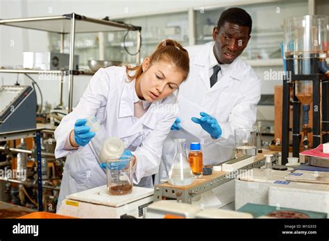 Focused Lab Technician Woman With Tubes And Worried Man Technician During Chemical Experiments