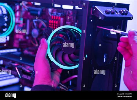 Man Puts Modern Fan With Blue Led Light In The Computer Using Screwdriver Stock Photo Alamy