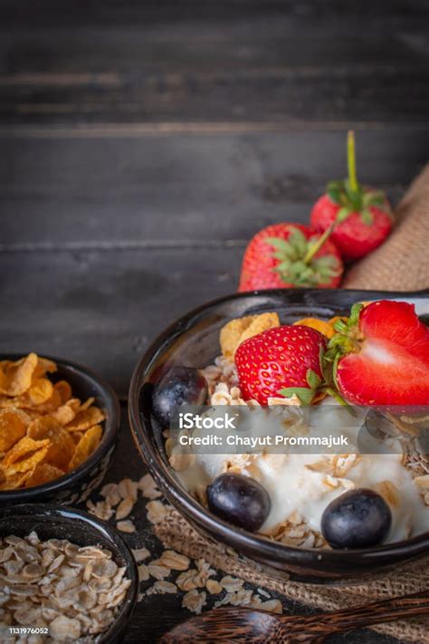 요구르트 믹스 오트밀 딸기 포도 토 핑에 검은 그릇에 숟가락 오트밀 콘플레이크와 딸기가 들어 있는 나무 테이블 0명에 대한 스톡 사진 및 기타 이미지 Istock