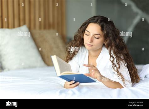 Concentrated Woman On A Hotel Bed Reading A Paper Book Stock Photo Alamy