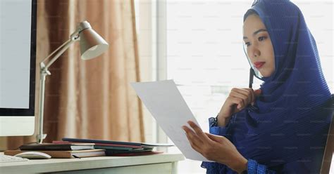 히잡을 쓴 생각에 잠긴 젊은 베트남 여성이 손에 든 재무 차트를 분석한다 사진 Unsplash의 성인 이미지