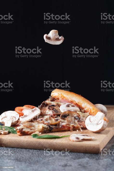 햄 토마토 치즈 양파 허브가 있는 커팅 우드 보드에 수제 이탈리아 피자에 떨어지는 버섯 조각이 어두운 돌 슬레이트 테이블에 놓여 있습니다 구도에 대한 스톡 사진 및 기타