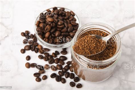 흰색 대리석 배경에 유리 항아리에 인스턴트 커피 콩 뜨거운 음료 재료 테이블에 인스턴트 커피 에스프레소 텍스트를 위한 장소입니다