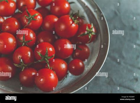 Raw Whole Washed Cherry Tomatoes In A Colander On A Dark Concrete
