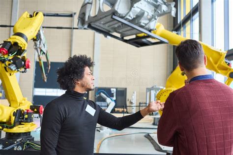Engineers Examining Robotic Gripper Arm During Industrial Automation Training Session Stock