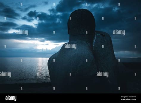 A Closeup Of A Statue Of A Person On The Shore Of The Sea In The