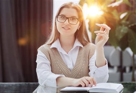 A Beautiful Young Girl In The Office Works With Documents Holds A Pen In Her Hand And Looks At