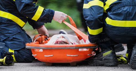 알아볼 수 없는 소방관들이 교통사고 후 부상당한 젊은 여성을 도로의 플라스틱 들것에 넣었습니다 닫다 사진 Unsplash의 구출 이미지