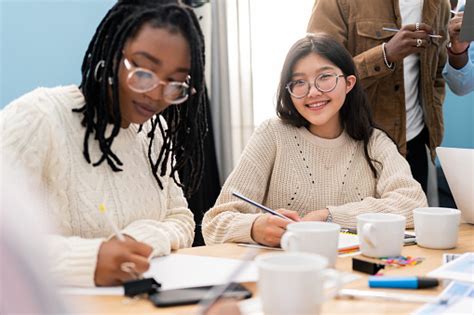 밝고 현대적인 사무실의 테이블에 함께 앉아있는 다양한 기업 동료의 미소 짓는 그룹의 초상화 그들은 문서를 작성하고 보고서 작성 초안 사무실에서 커피를 마시고 있습니다