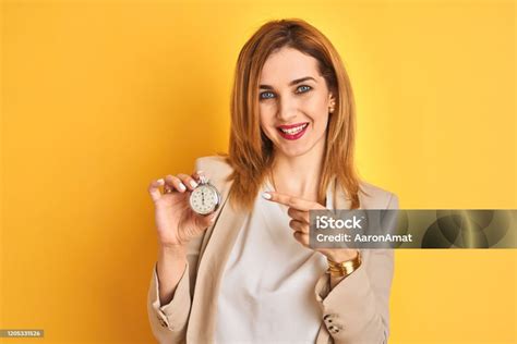 빨간 머리 백인 여자 들고 스톱워치 위에 노란색 고립 된 배경 매우 행복 가리키는 손과 손가락 가리키기에 대한 스톡 사진 및 기타 이미지 Istock