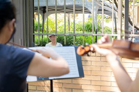 Keluarga Pakai Masker Bermain Biola Untuk Wanita Senior Di Balik Pagar