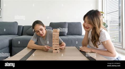 Two Asian Woman Enjoy Playing Wooden Blocks Game In The Living Room Players Take Turns Removing