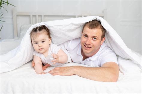 Pai E Filha Bebê Na Cama Debaixo Do Cobertor Sorrindo E Abraçando Feliz