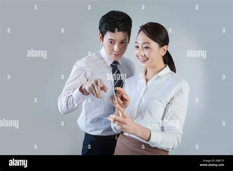 Man And Woman In Formal Outfits Pointing At The Touch Screen Held By The Woman Stock Photo Alamy