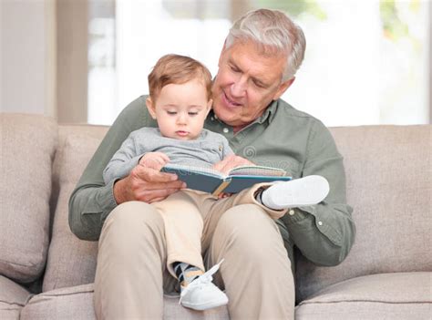 Story Time With Grandpa A Handsome Senior Man Reading To His Grandson While Sitting On The Sofa