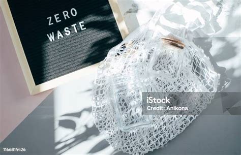 폐기물 제로 친환경 컨셉 회색 배경에 텍스트 제로 폐기물과 유리 항아리와 병과 편지 보드 메쉬 가방 상단 보기 플랫 레이 0명에