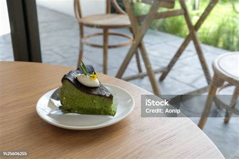 녹차 치즈 케이크 테이블 배경에 휘핑 크림 치즈를 얹은 수제 말차 치즈 케이크 한 접시 화이트 플레이트에 찻잎을 곁들인 일본 말차 녹차 케이크 가루 설탕에 대한 스톡 사진