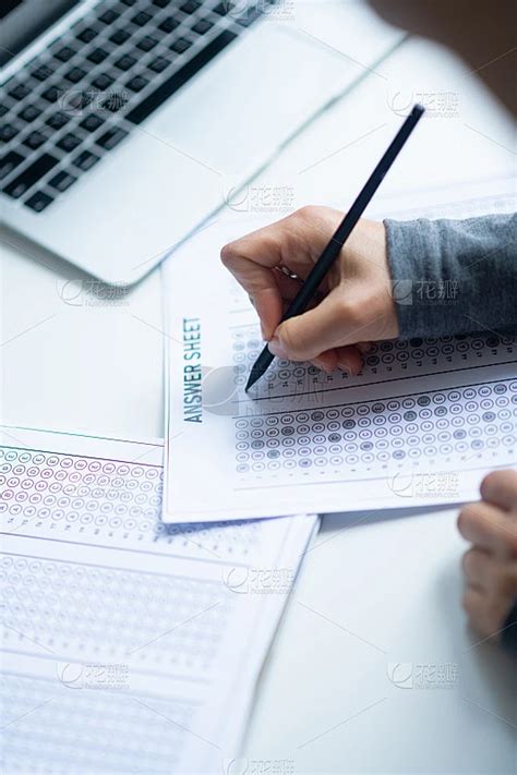 老师坐在笔记本电脑旁边批改学生的试卷素材 花瓣网