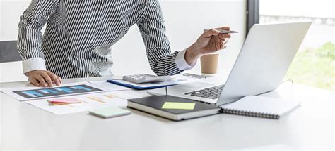 노트북 화면과 테이블에 누워 문서를 가리키는 여자 검은 양복을 입은 비즈니스 여성은 문서에서 정보를 확인 앉아 그는 회사