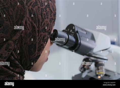 Young African Female Scientist Looking Through A Microscope In A