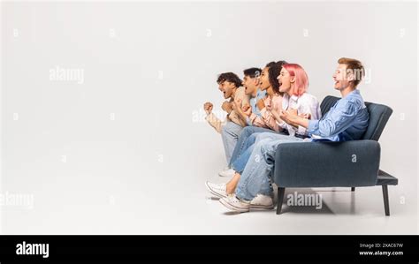 Diverse Group Of Friends Cheer Excitedly While Sitting On Couch Stock