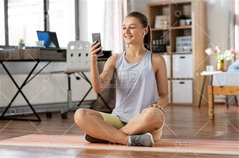 电话高清图片 运动、健身和健康的生活方式概念 微笑的少女带着智能手机和耳机坐在家里的瑜伽垫上。带电话和耳机在家锻炼的女孩 人像图片免费下载格式5760像素编号67139125 千图网