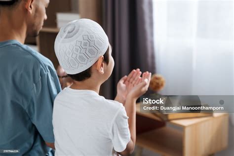 라마단 기간 동안 함께 기도하는 무슬림 가족 신앙 영성 종교적 헌신을 상징하는 가정에서 카림 아버지 코란을 손에 들고 이슬람 전통을 가르치는 아버지 25 29세에 대한 스톡